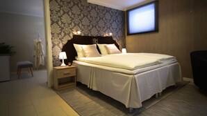 Uma cama bem arrumada com lençóis brancos, um abajur e uma mesa de cabeceira.