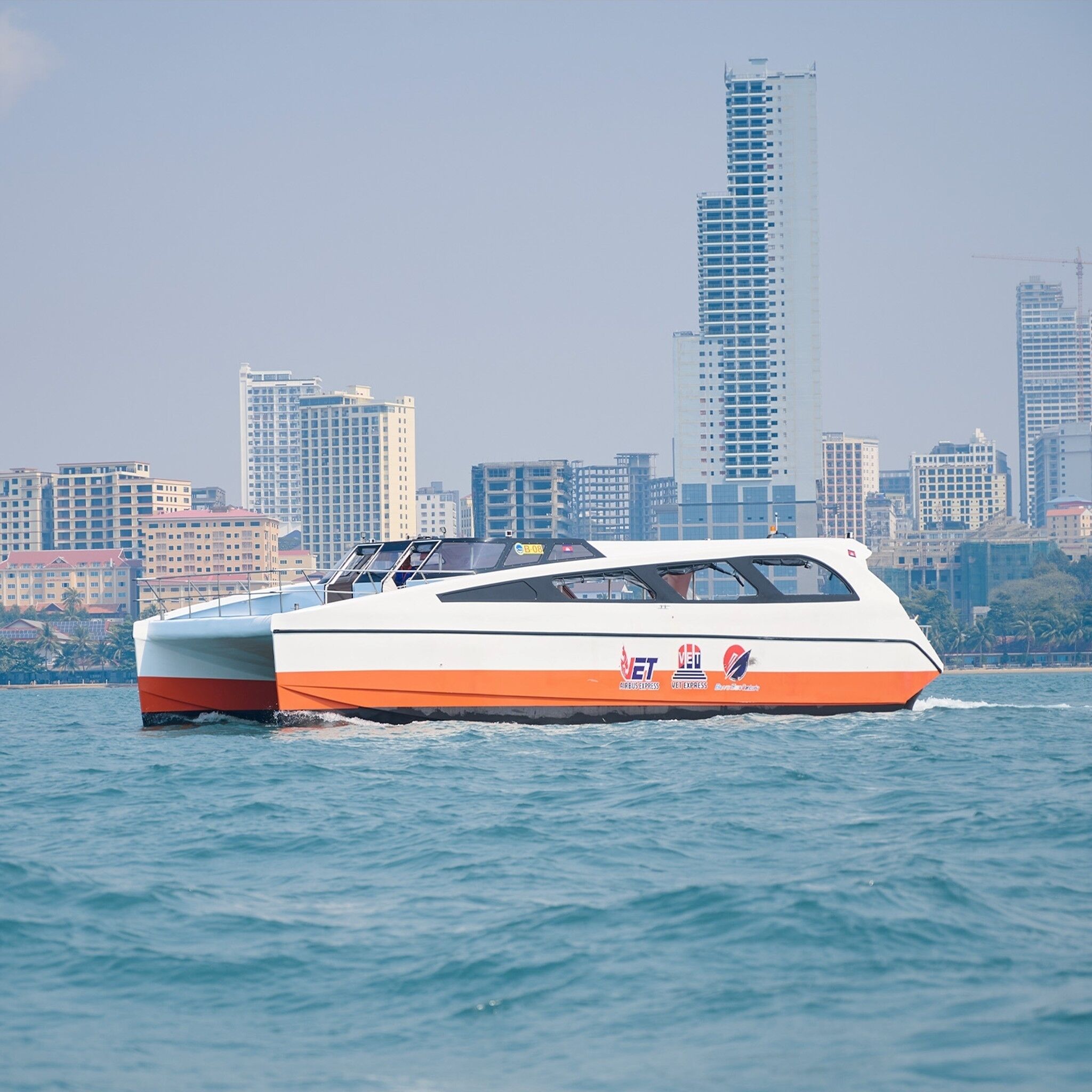 Um barco rápido com design aerodinâmico, navegando em águas com um horizonte urbano ao fundo.