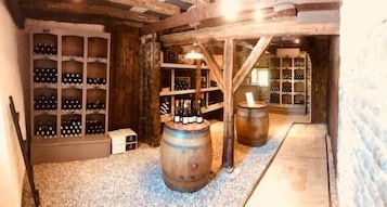Uma adega rústica com prateleiras e barris de madeira, provavelmente utilizada para armazenamento de vinho.