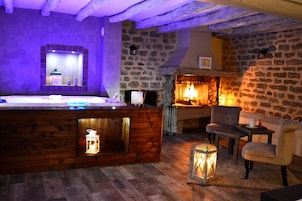 Um quarto aconchegante com lareira de pedra, móveis de madeira e um espaço bar com um candeeiro.