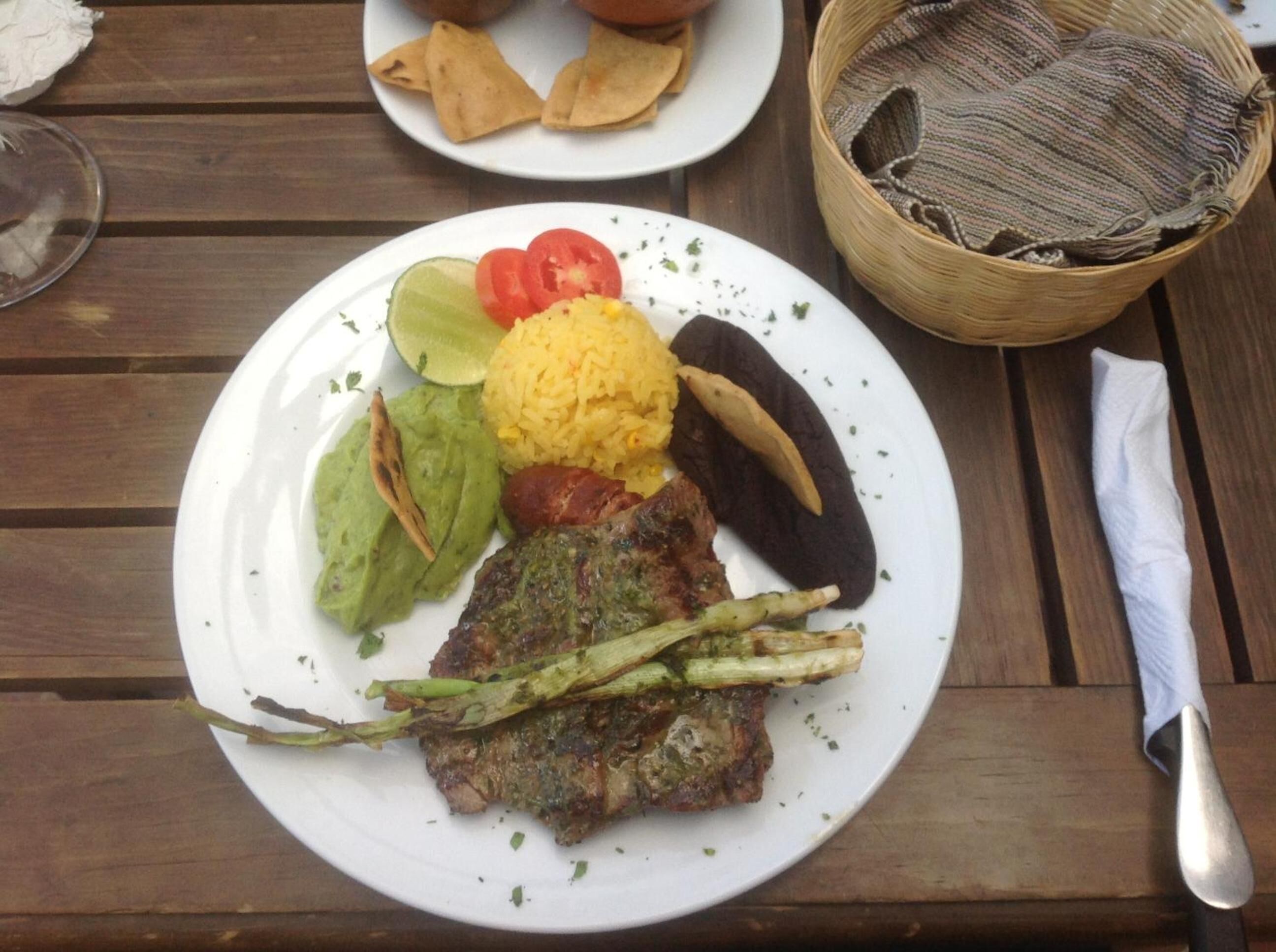 Um prato com carne grelhada, abacate, arroz e legumes.