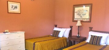 Quarto de hotel com duas camas, uma cômoda e um quadro na parede.
