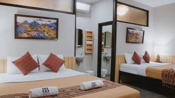 Quarto de hotel com duas camas, banheiro e obras de arte nas paredes.