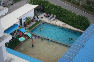 Piscina ao ar livre com escorrega e pequena área de deck.