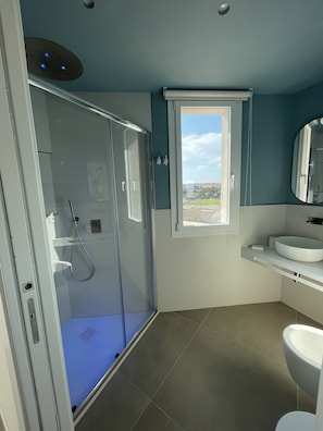 Quarto casal superior, 1 cama de casal, sacada, vista para o mar | Banheiro | Chuveiro, chuveiro com efeito de chuva, produtos de toalete grátis 