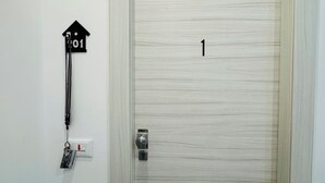 Uma porta com o número 1, uma fechadura e um leitor de cartão magnético na parede.