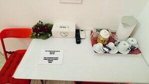 Uma mesa com um sinal de WiFi emoldurado, um controle remoto, uma caixa de lenços de papel, um tabuleiro com xícaras e uma chaleira, e um bilhete.