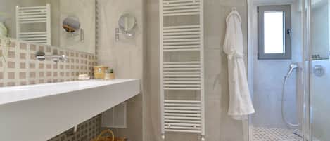 Um banheiro moderno com toucador branco, box de vidro e porta-toalhas.