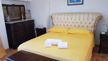 Quarto com uma cama grande, cômoda, mesa de cabeceira e um quadro na parede.