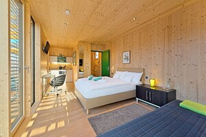 Quarto moderno com cama, mesa de cabeceira e área de trabalho com cadeira.