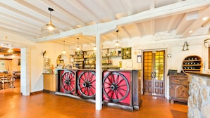 Uma área de bar com balcão de madeira, rodinhas vermelhas e luminárias pendentes.