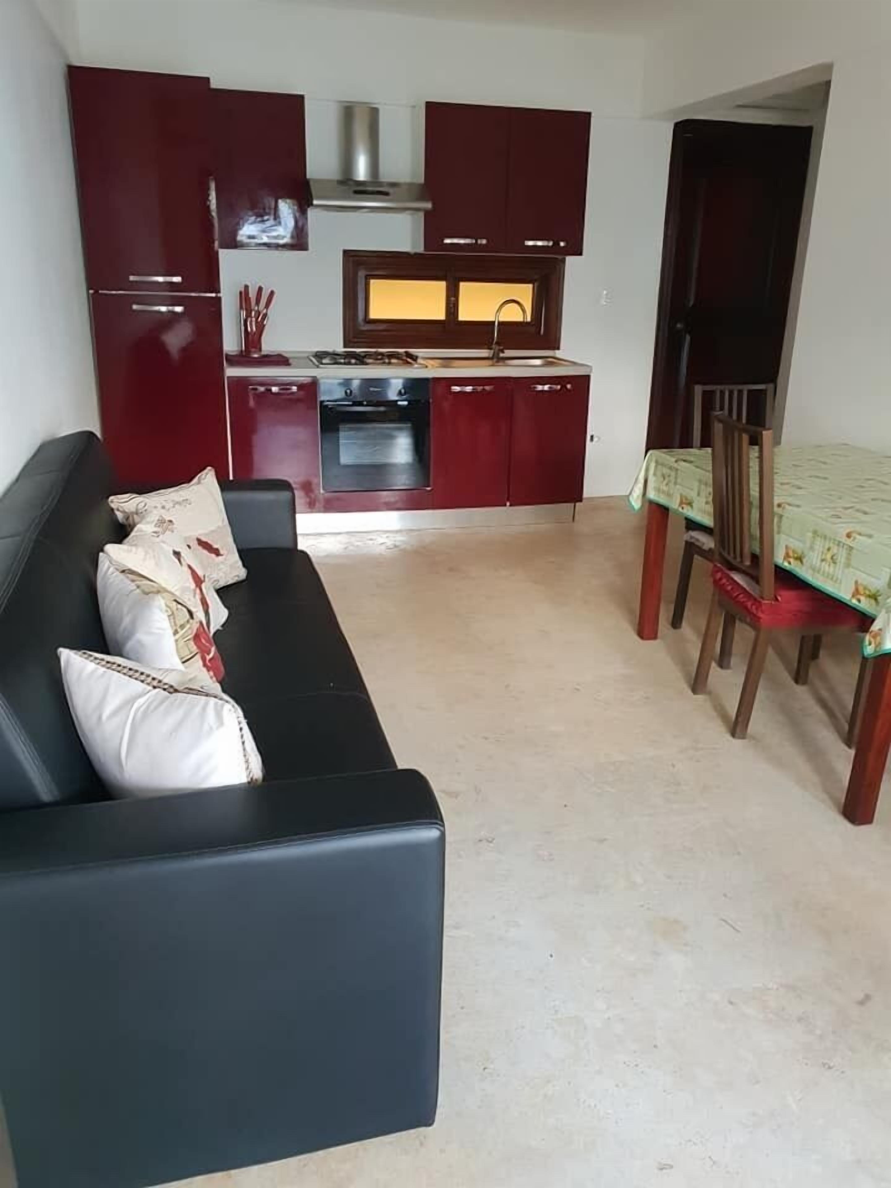 Um espaço compacto com cozinha compacta, área de refeições e sofá com almofadas.