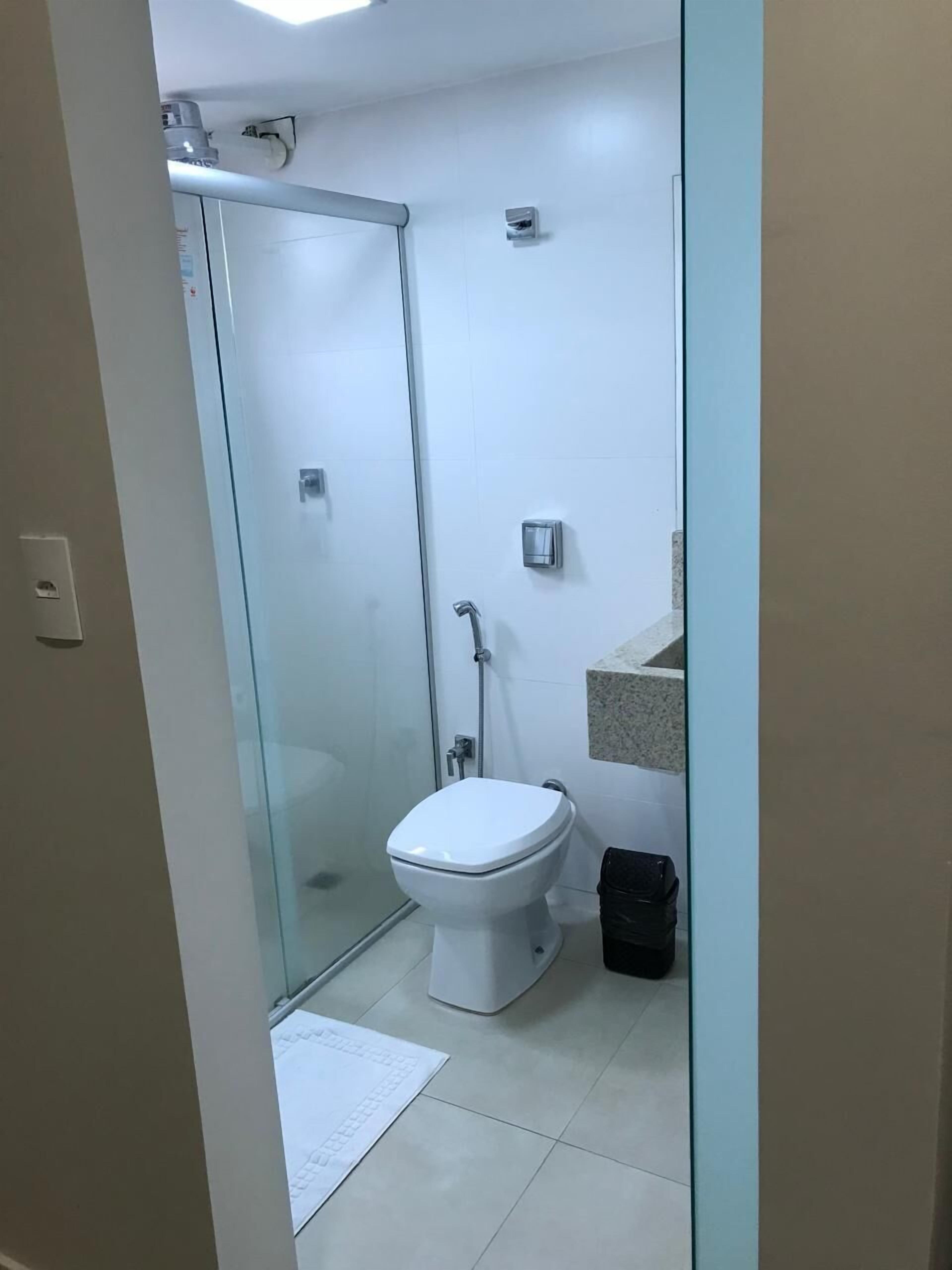 Uma casa de banho moderna com cabine de chuveiro em vidro, sanita e lavatório com bancada de granito.