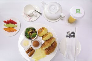 Uma mesa posta com diversos alimentos, incluindo croissants, uma salada e um prato de legumes fatiados.