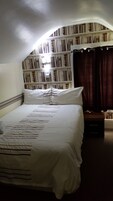 Quarto com cama grande, estante e janela com cortinas.