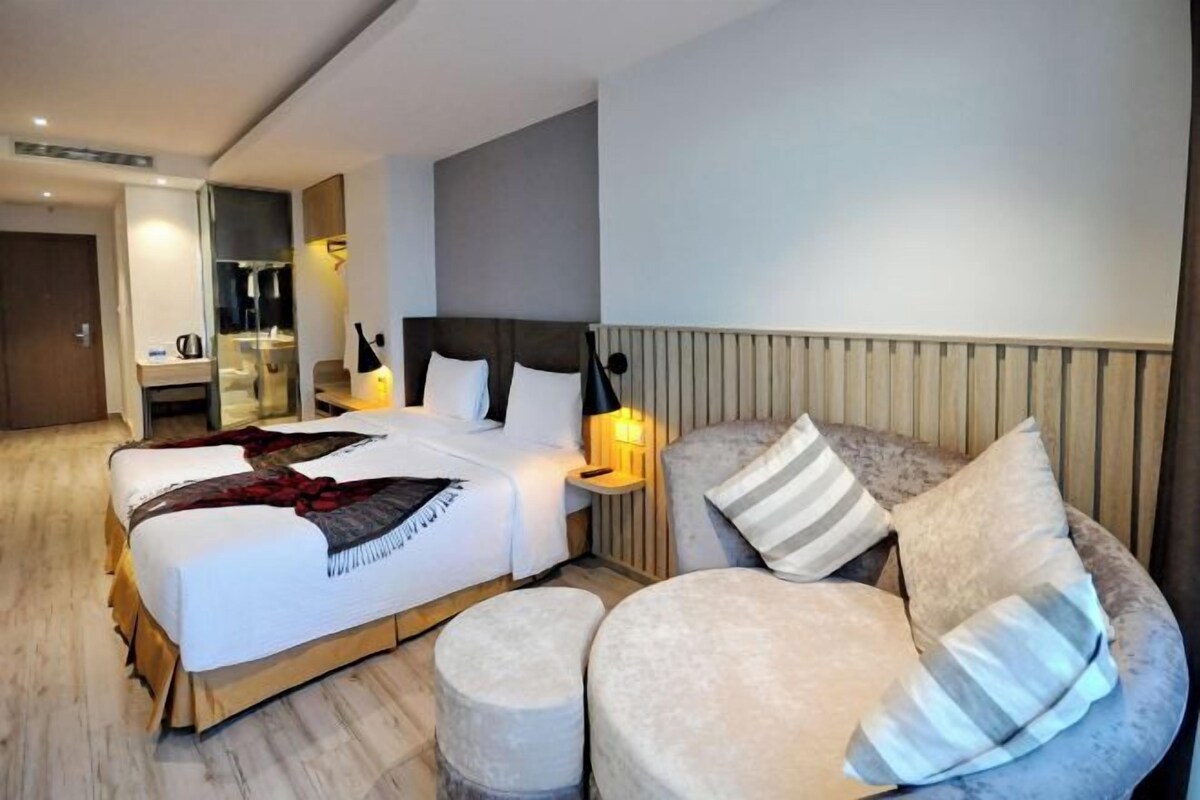 Quarto de hotel moderno com uma cama grande, um sofá e uma pequena mesa.