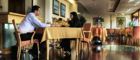 Um restaurante com piso de madeira, mesas redondas e cadeiras.