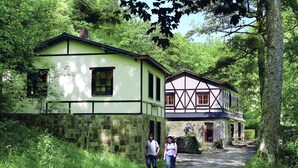 Uma casa tradicional com fachada de pedra e uma extensão em estilo Tudor.
