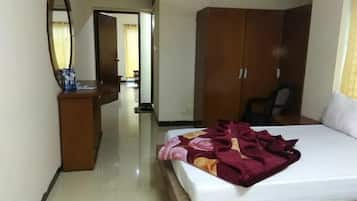Quarto de hotel com uma cama, um guarda-roupa de madeira, uma secretária com espelho e uma cadeira.