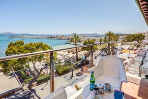 Uma varanda com vista para a costa, incluindo uma praia e um porto de recreio.