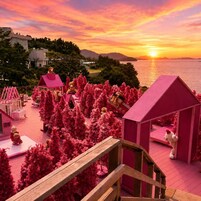 Um deck com estruturas rosadas e árvores, com vista para um corpo d'água e montanhas.