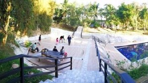 Um parque com uma passarela pavimentada, bancos e uma pequena área de piscina rodeada por árvores.