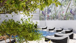 Área de piscina com espreguiçadeiras e um mural de fauna tropical.