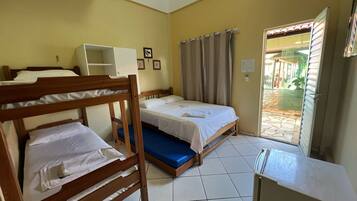 Quarto com duas beliches, uma mesa e uma janela com cortinas.