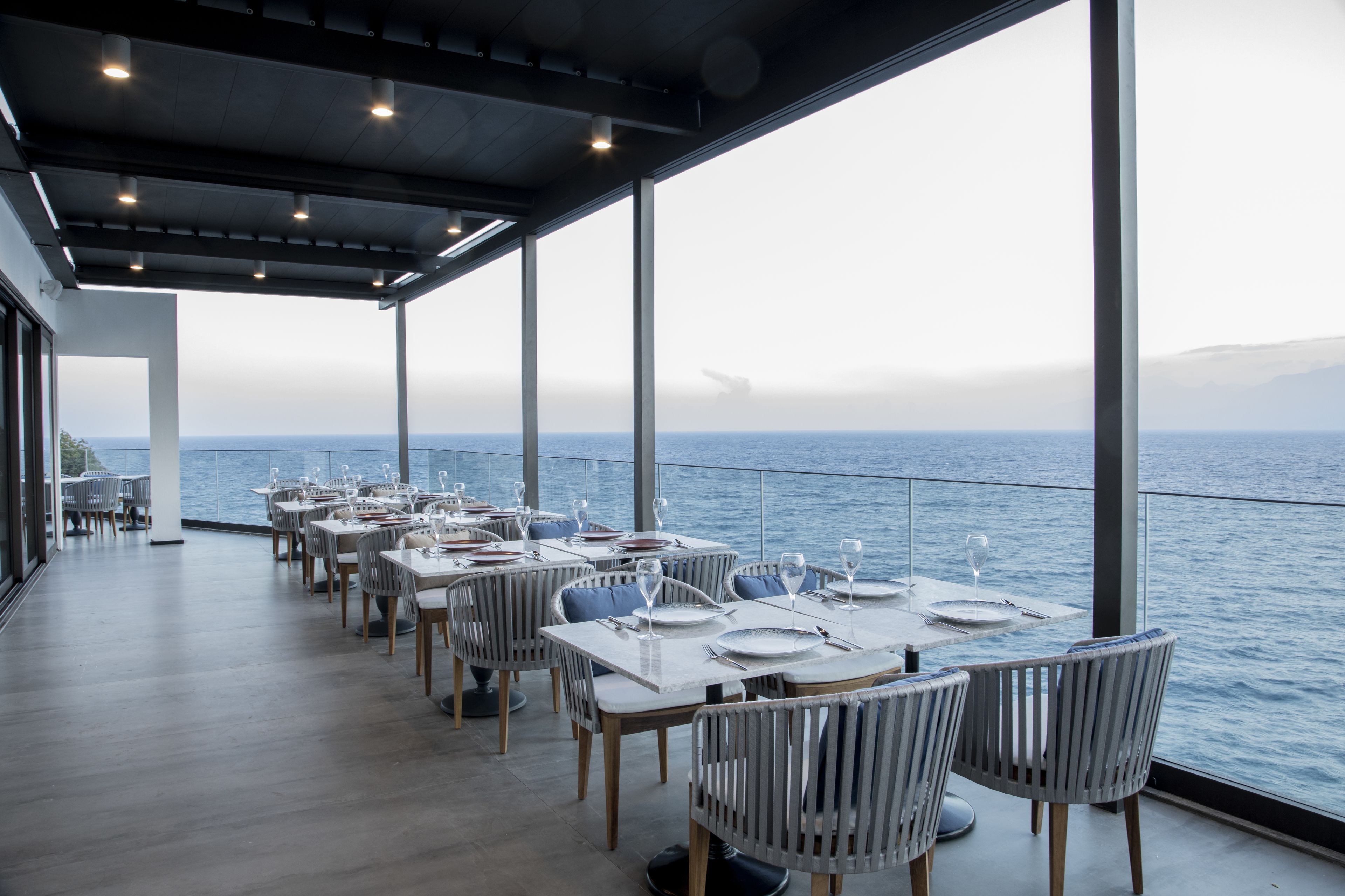 Restaurante com mesas preparadas para refeições, com vista para um corpo de água.