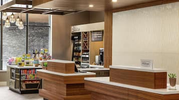 Uma área de recepção de hotel com balcões de madeira, um minibar e um espaço para café.
