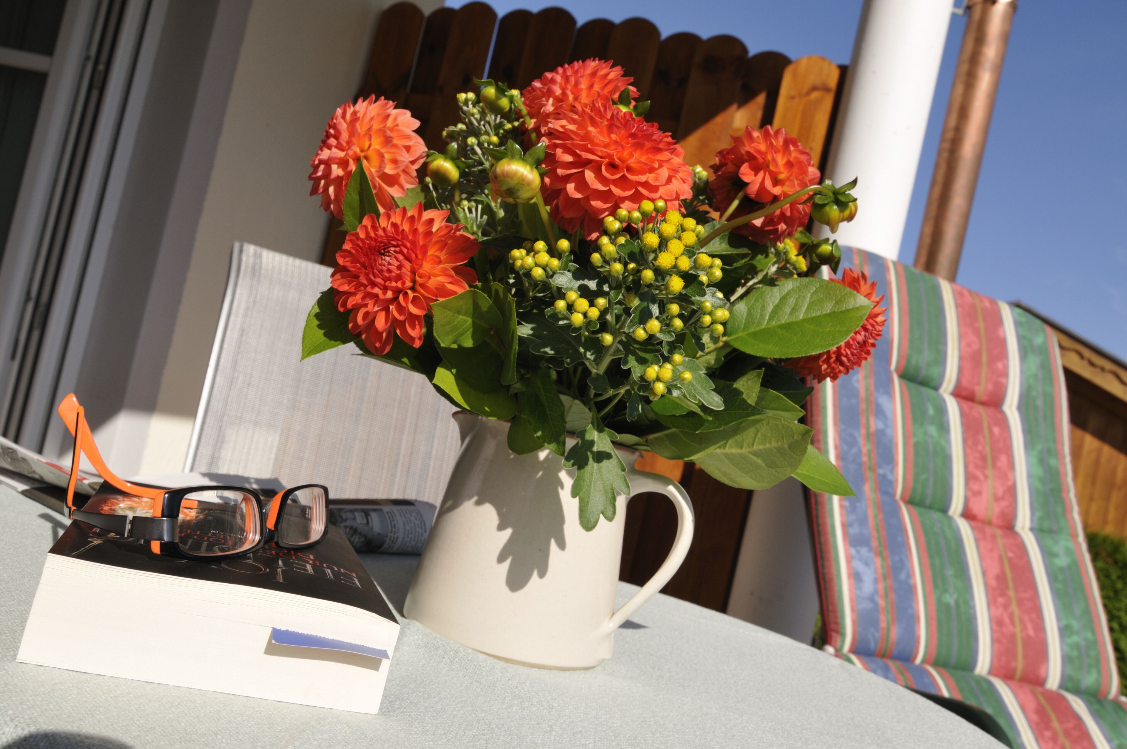 Uma caneca de cerâmica branca com uma composição floral sobre uma mesa.