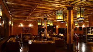 Um restaurante acolhedor com vigas de madeira, lanternas penduradas e assentos confortáveis.