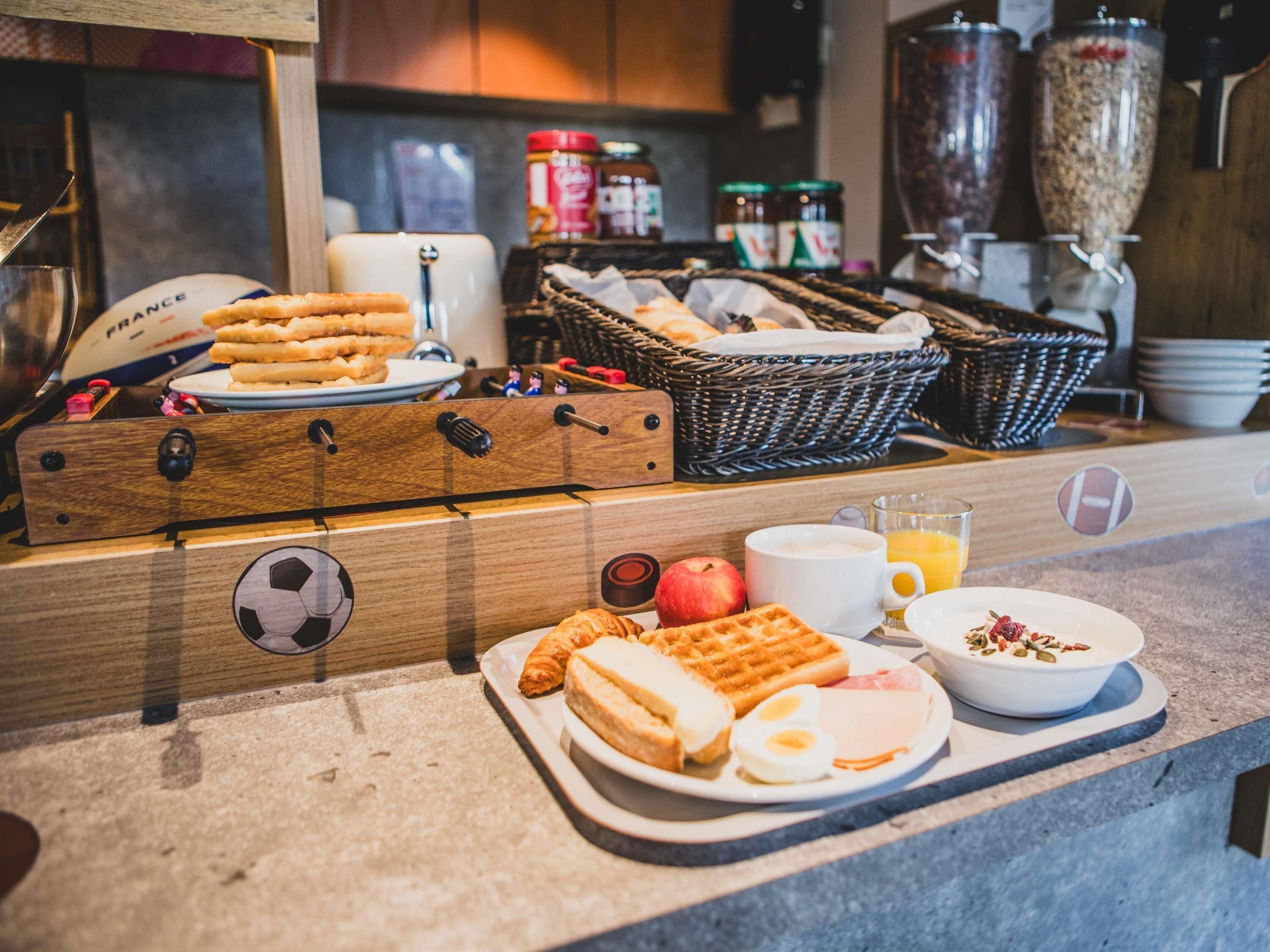 Buffet de café da manhã com waffles, ovos, torradas e frutas.