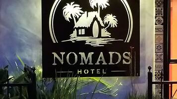 Placa do Hotel Nomads com design de palmeira e cabana.