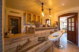 Uma área de recepção com balcão de madeira, mesa de atendimento e um banquinho de bar.