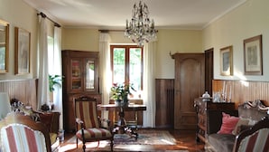 Uma sala de estar ampla com um candelabro, móveis de madeira e um tapete grande.