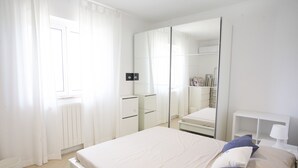 Quarto moderno com uma cama grande, um guarda-roupa e um espelho.