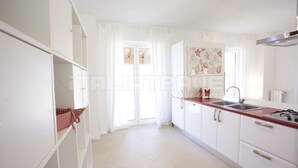 Cozinha moderna com armários brancos, bancada vermelha e pia de aço inoxidável.