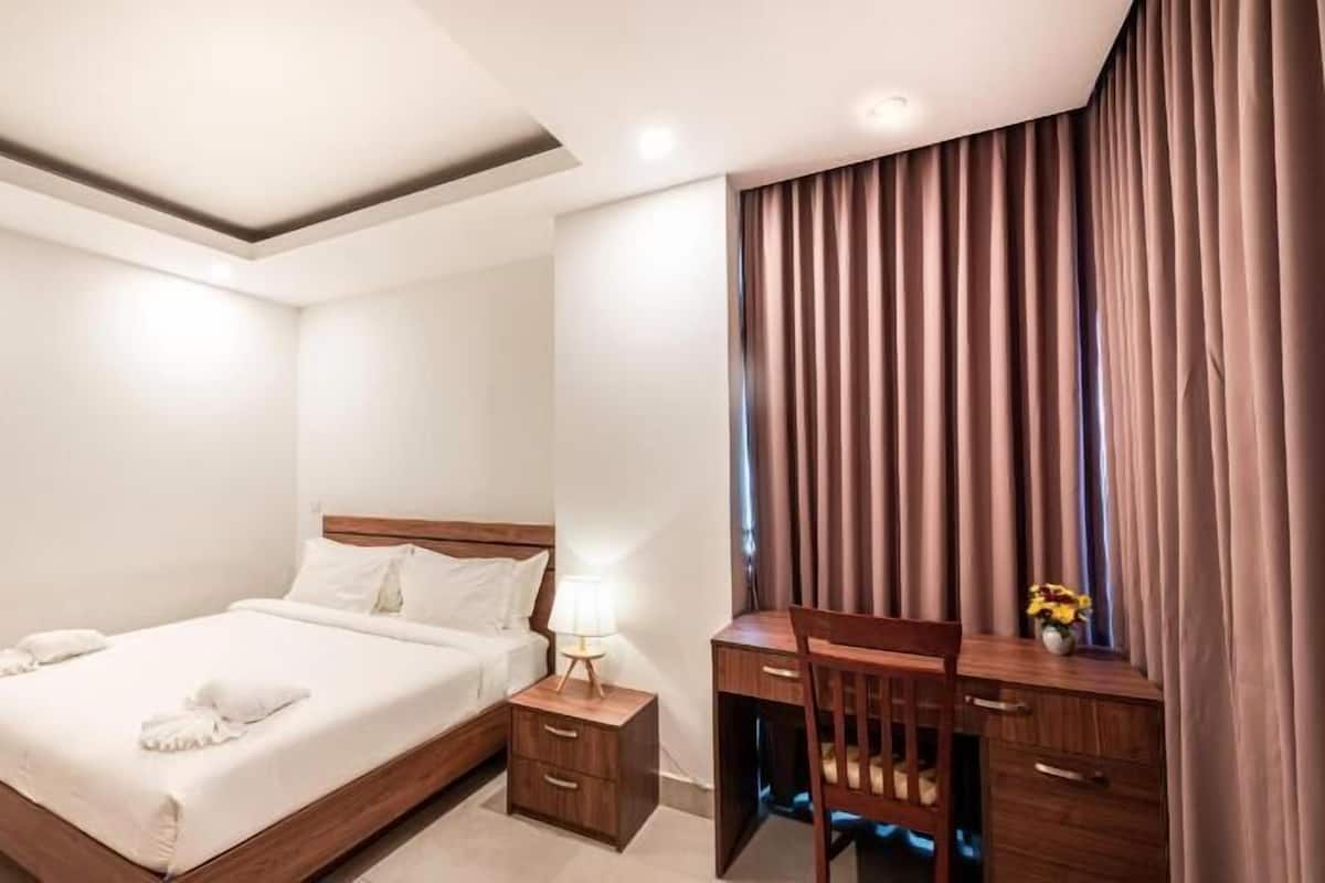 Quarto com cama, mesa de cabeceira, escrivaninha, cadeira e cortinas.