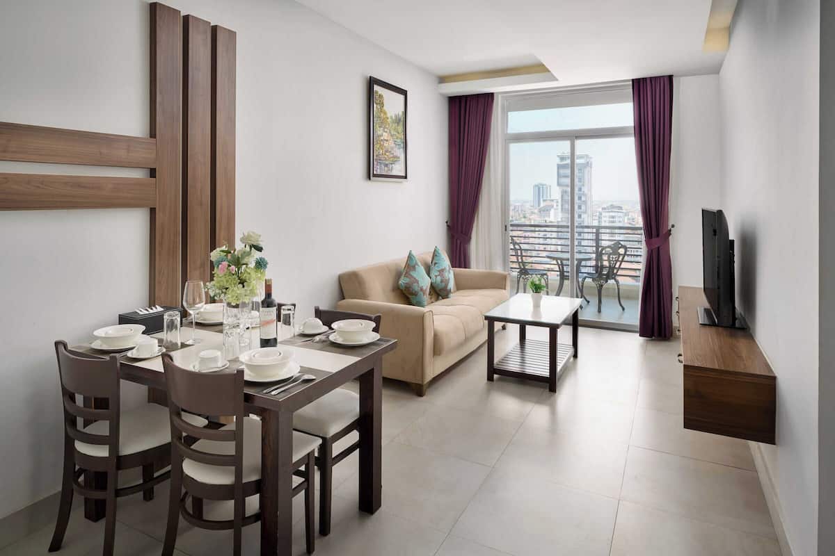Uma sala de estar moderna com área de jantar, sofá, televisão e varanda com vista para a cidade.