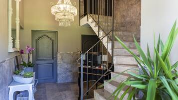 Uma escadaria com corrimão de metal, um candelabro e uma porta com painel decorativo.