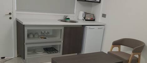 Um espaço compacto com cozinha compacta, área de refeições com mesa e cadeiras e um sofá.