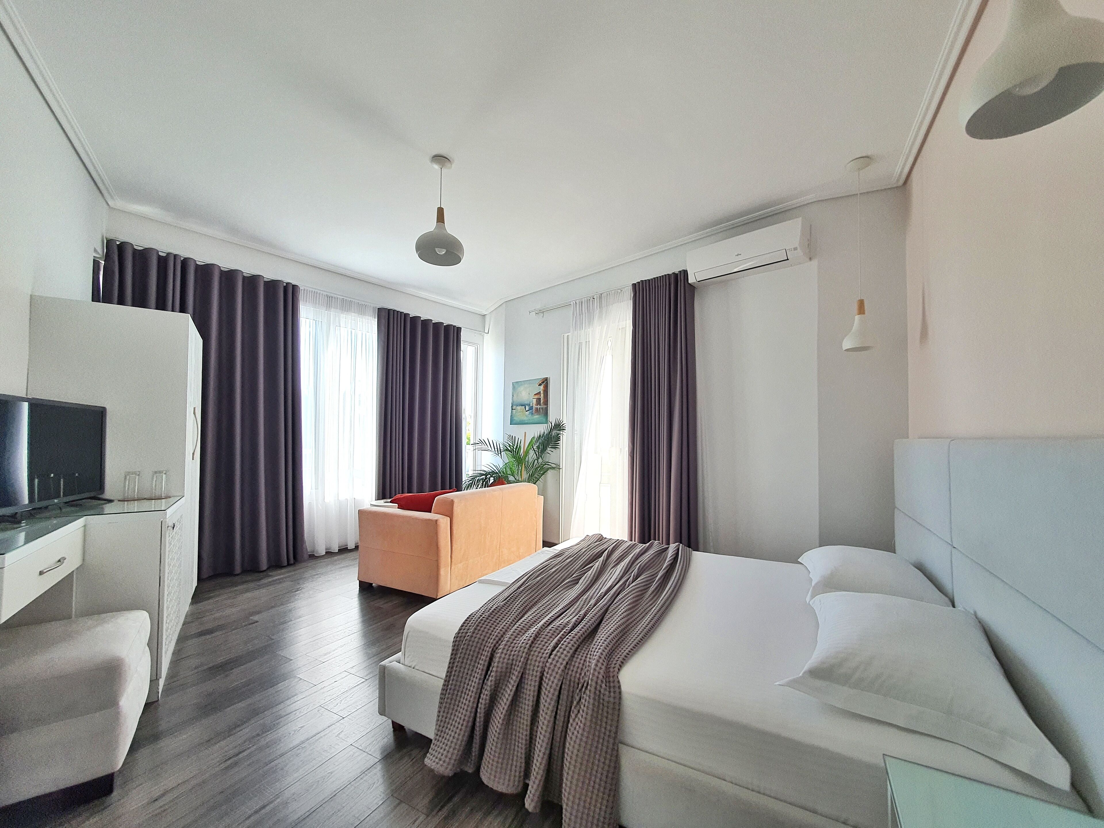 Quarto de hotel moderno com uma cama, uma escrivaninha, uma cadeira e uma televisão.