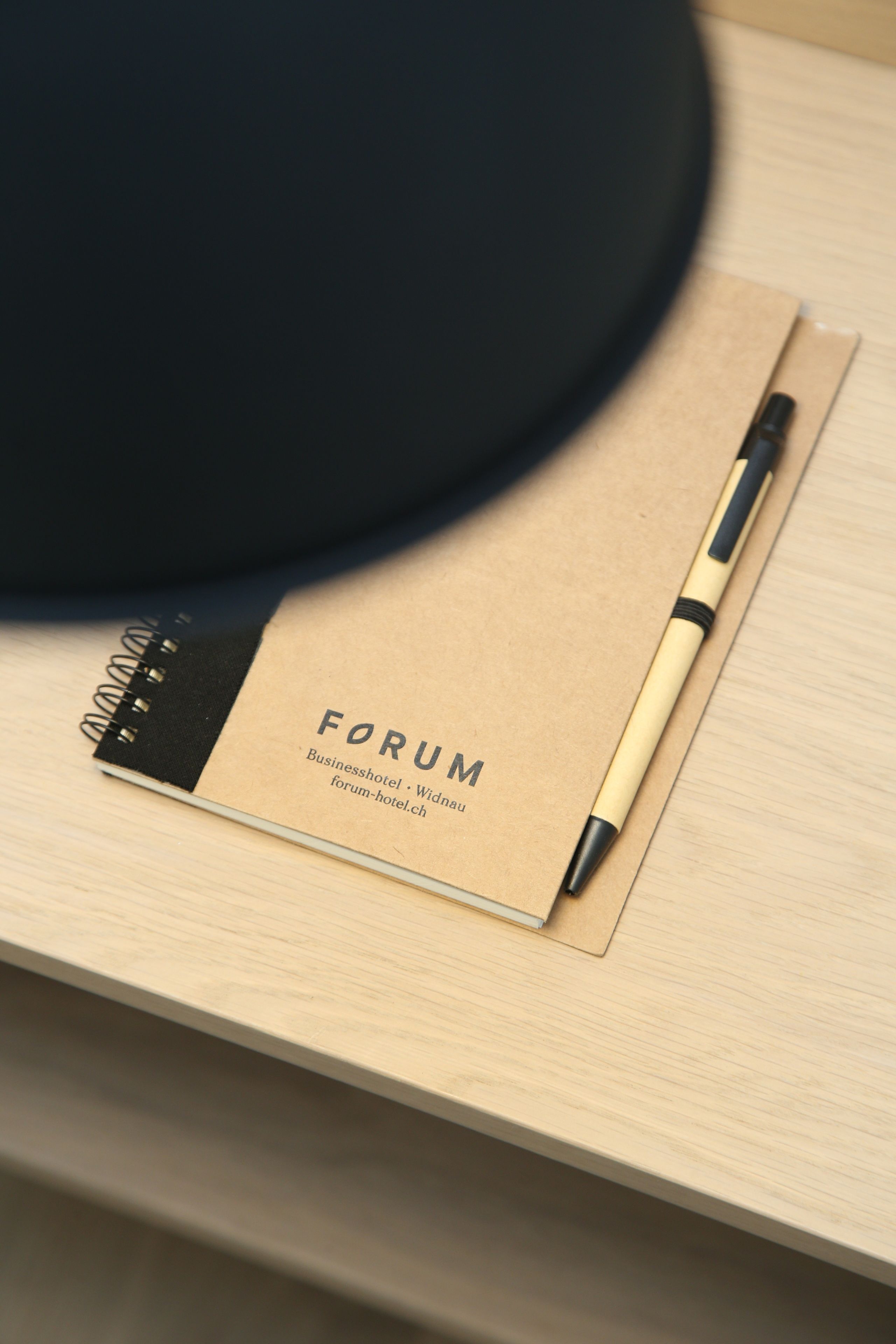 Um caderno com o título 'FORUM' e uma caneta sobre uma superfície de madeira.