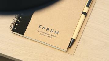 Um caderno com o título 'FORUM' e uma caneta sobre uma superfície de madeira.