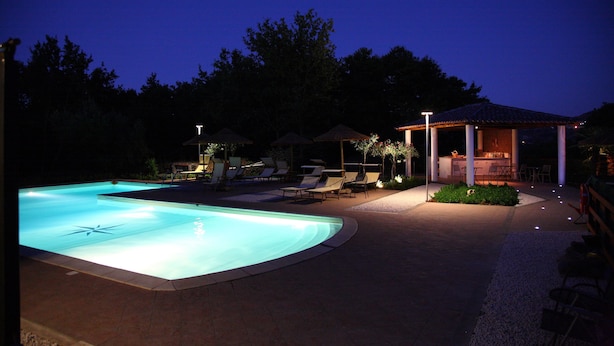 Piscina com espreguiçadeiras e um gazebo.