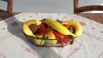 Uma cesta de frutas sobre uma mesa com toalha de mesa estampada.