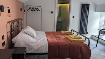 Quarto com cama, escrivaninha, radiador e porta para um banheiro.