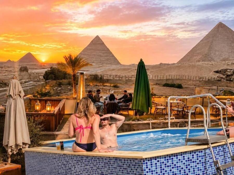 Piscina com vista para pirâmides ao pôr do sol.