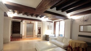 Uma sala de estar ampla com um sofá branco, uma mesinha e uma lareira. Uma escada leva a outro andar.